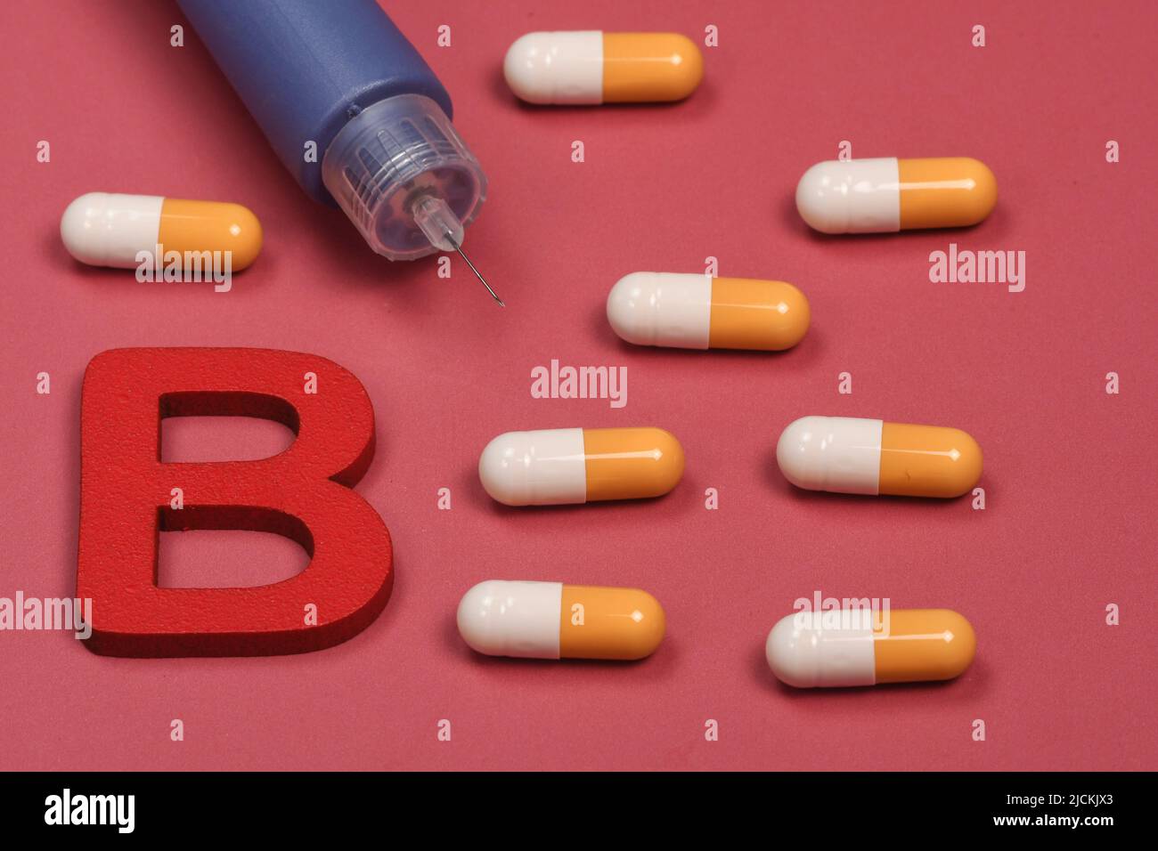 yellow and white medicine capsules on red background and insulin pen ...