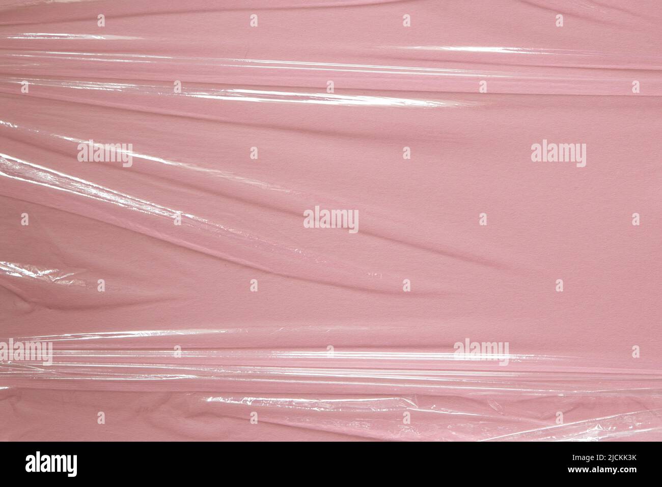Transparent plastic wrap on pink color background. Crumpled wrinkled ...