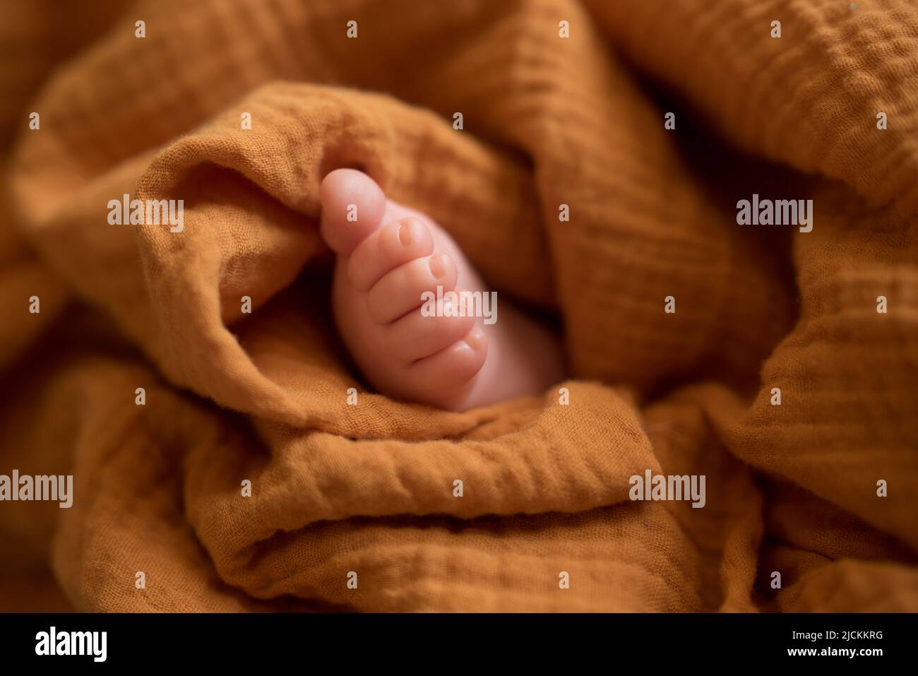 Little child's foot in orange clothes, macro photo of leg and fingers ...