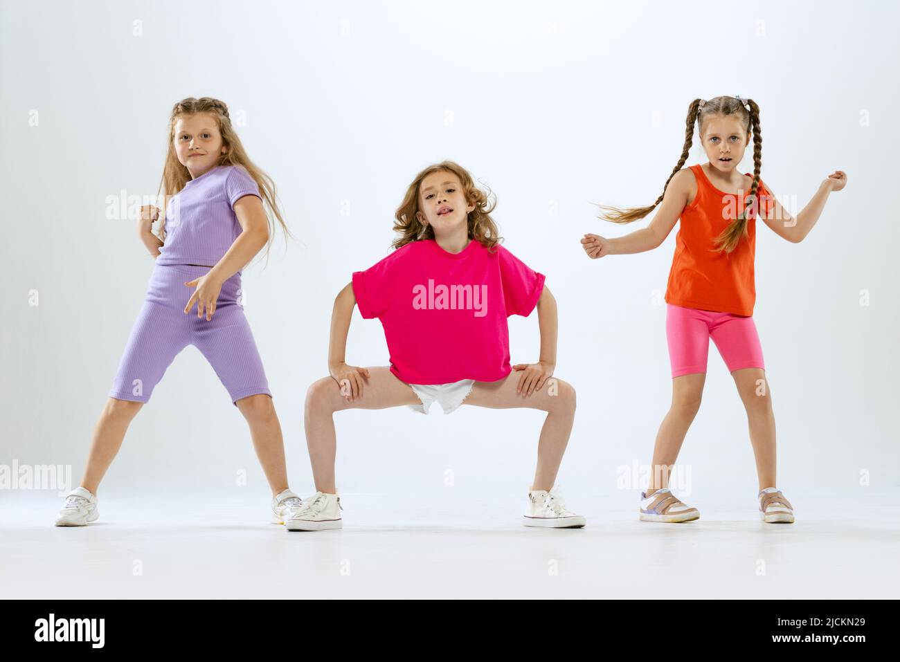 Three little girls, kids in bright colorful clothes dancing, posing ...