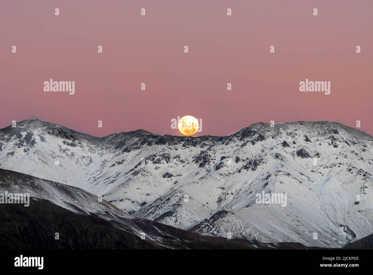 a wide shot of a Super moon rising over Mount Dobson on the shores of ...