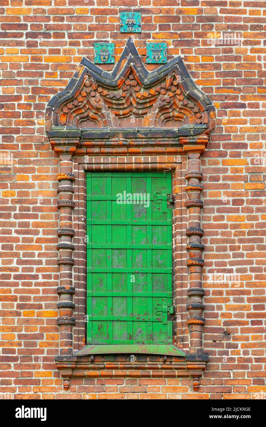 A picturesque window of an old brick church with metal shutters and ...