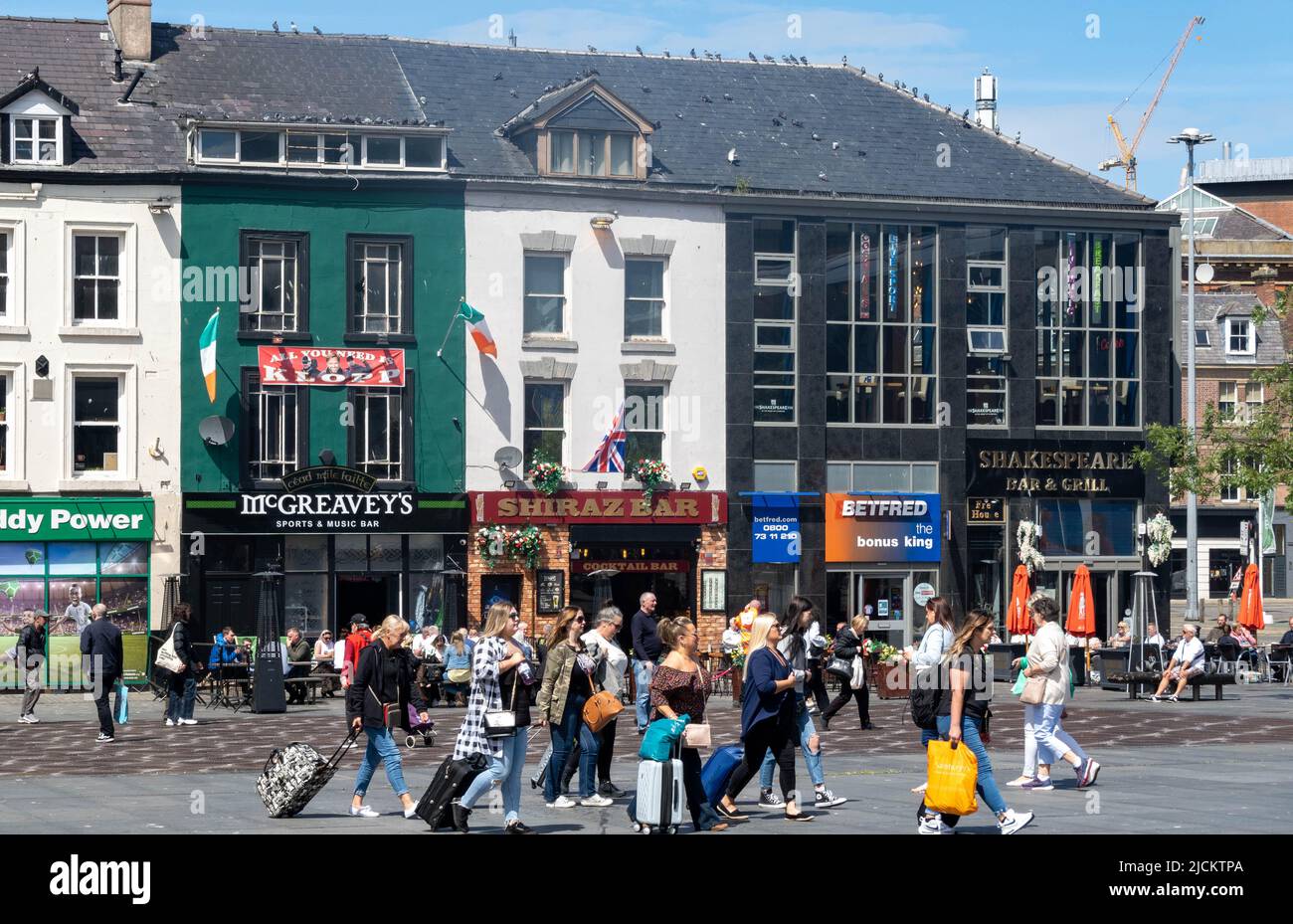 Tourist with rolling luggage passing alfresco bars in Williamson Square ...