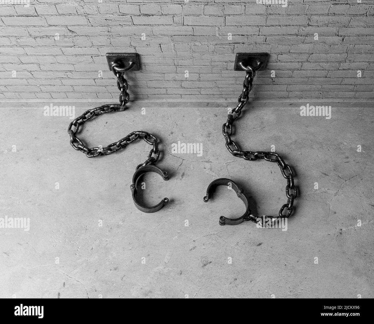 A set of empty old iron shackles draped on the floor connected to an ...