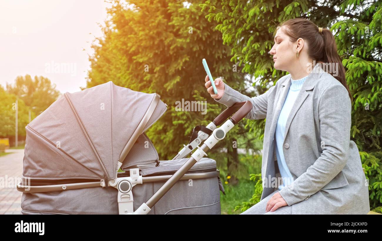 Woman checks social networks rocking baby in stroller Stock Photo - Alamy