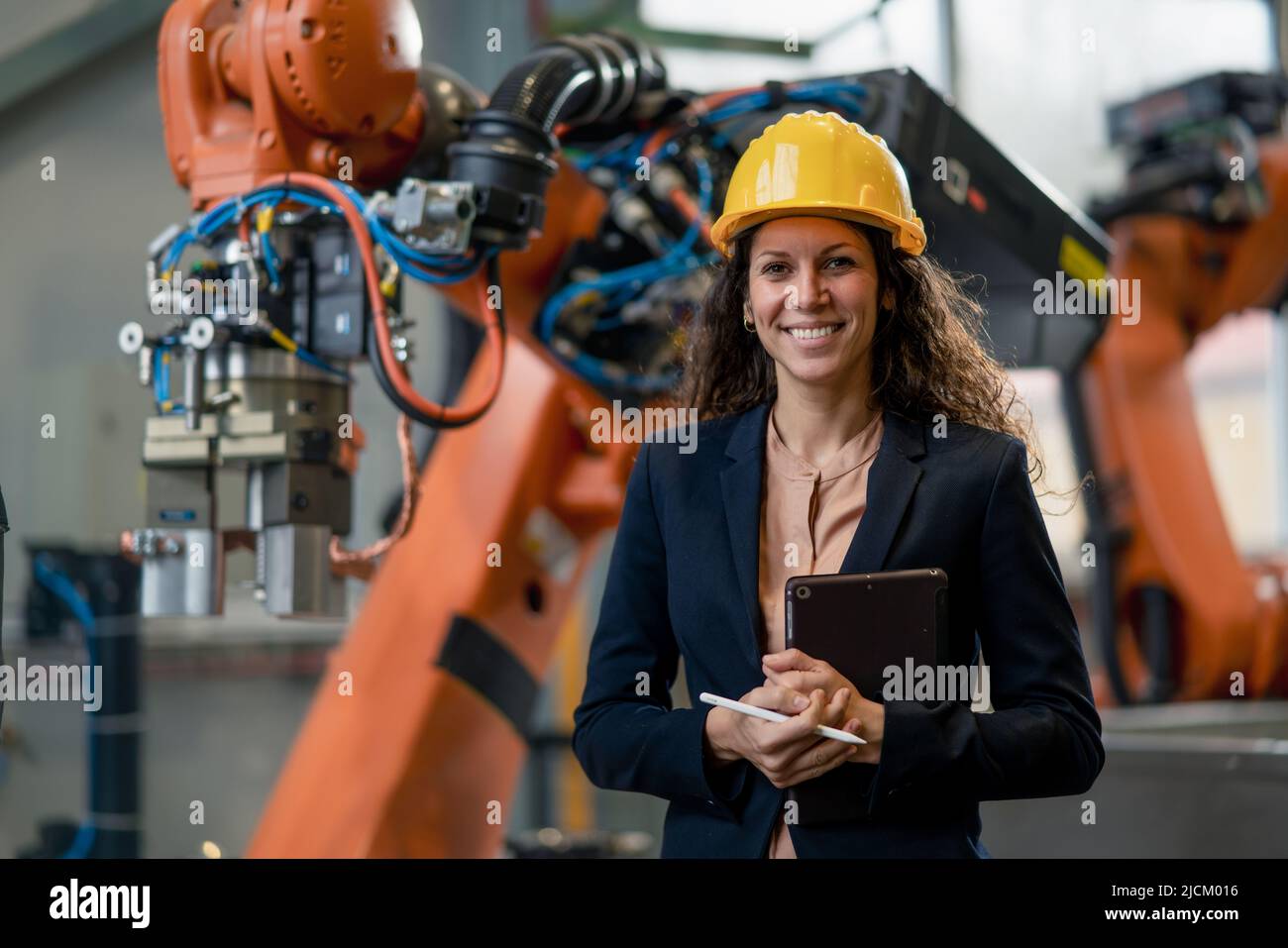 Automation female engineer with tablet for programming robotic arm in ...