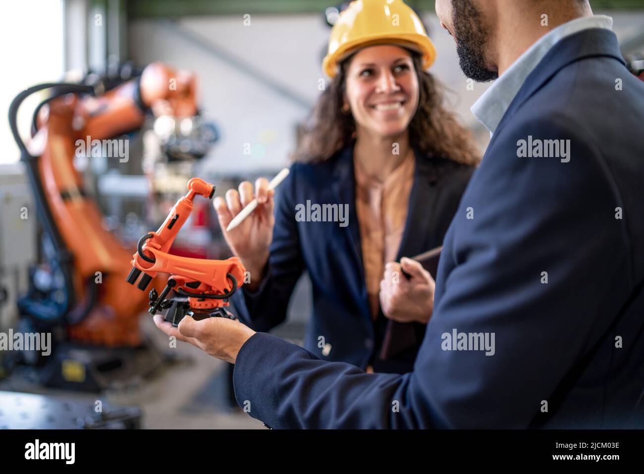 Man engineer holding model of industrial robotic arm and showing to ...