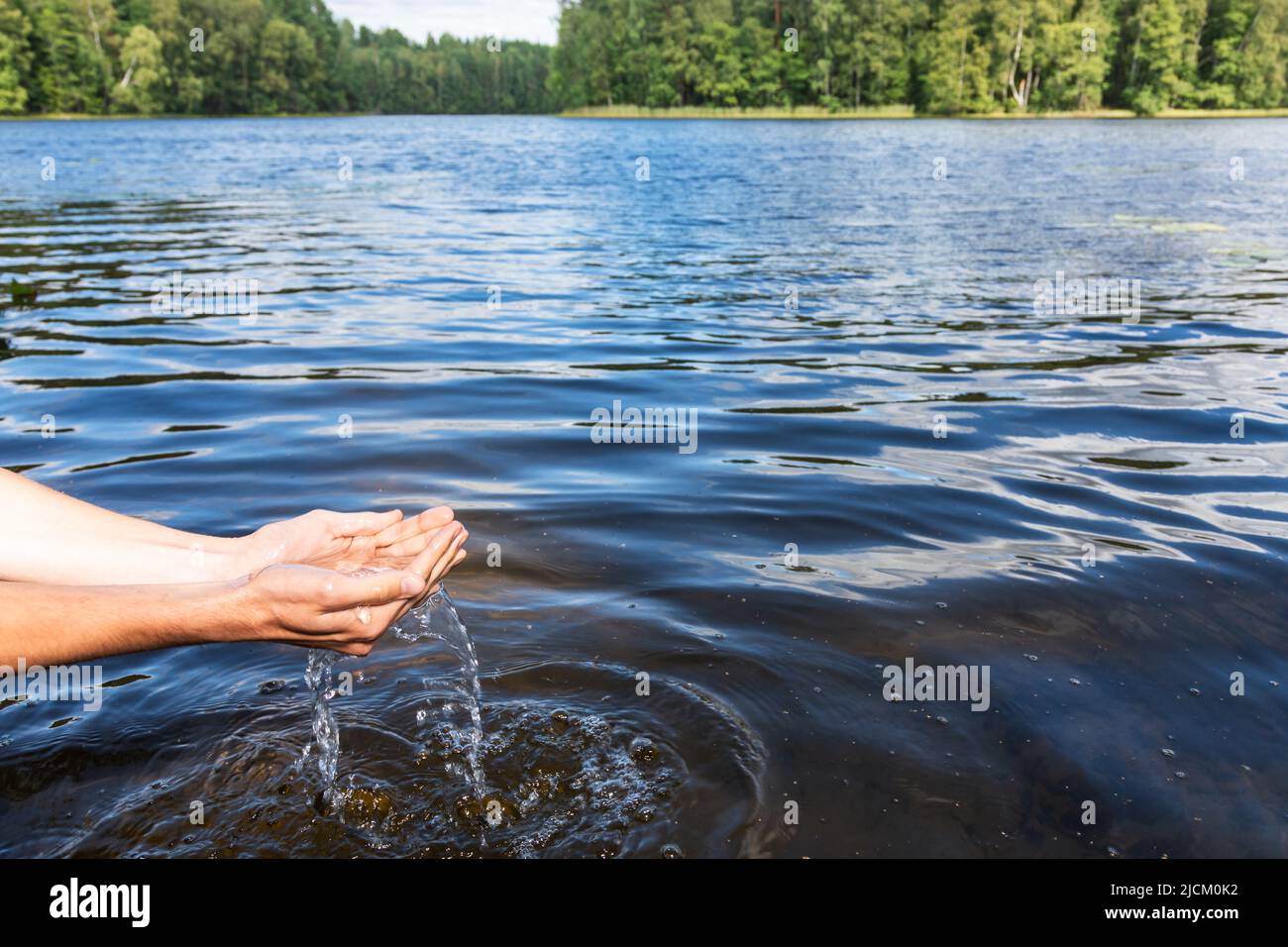 Person scoops up raw water from a lake. Natural water resources ...