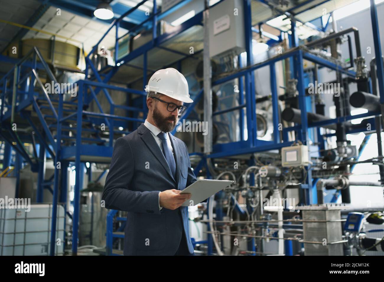 Chief Engineer in the hard hat walks through industrial factory while ...