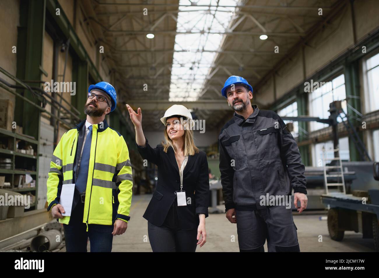 Manager supervisors and industrial worker in uniform walking in large ...