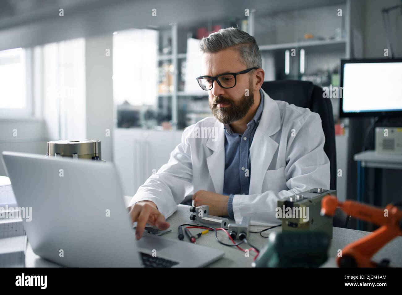 Robotics engineer working on desing of modern robotic arm aand sitting ...