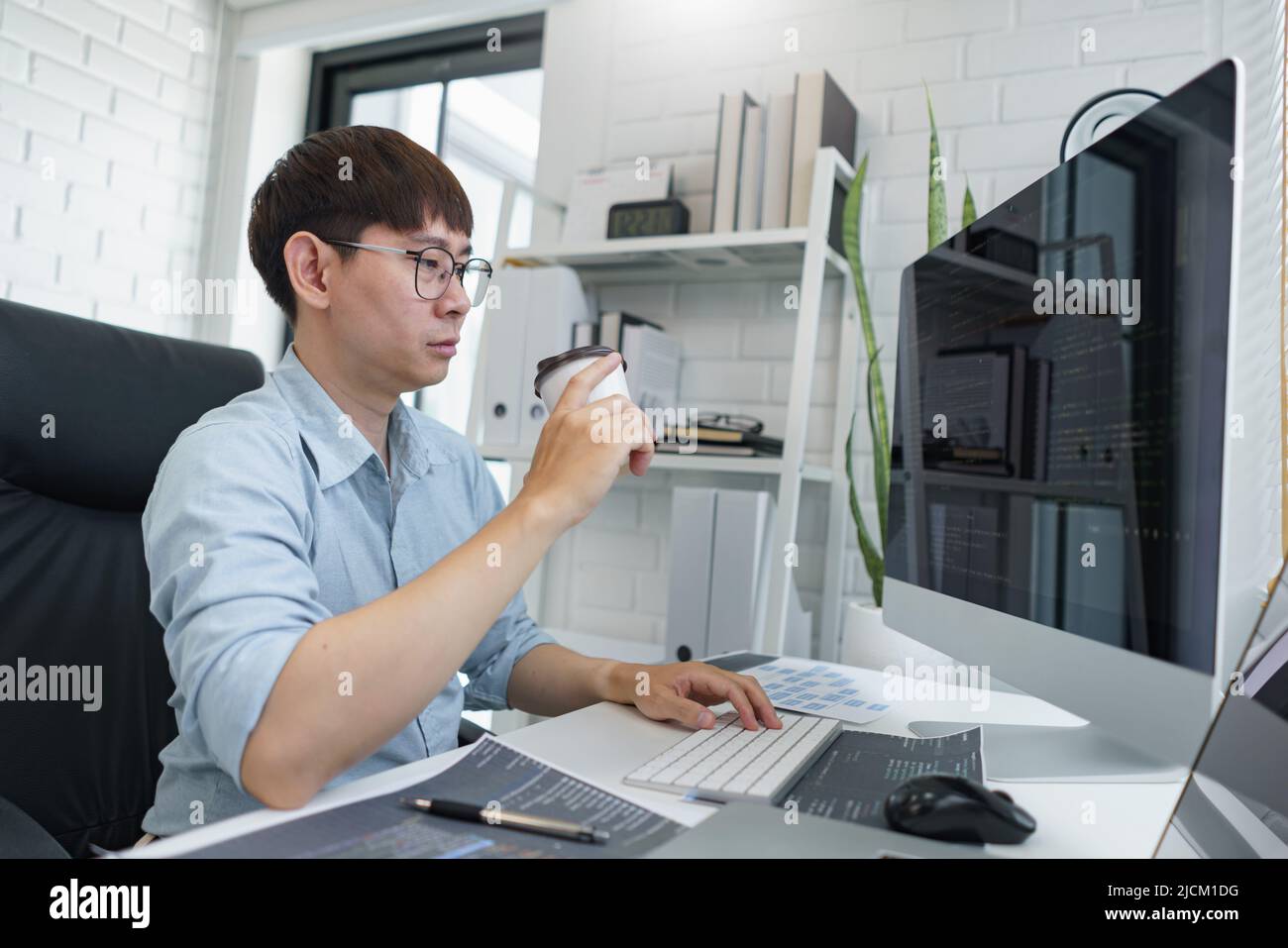 Software development concept, Male programmer checking website programming and drinking coffee ...