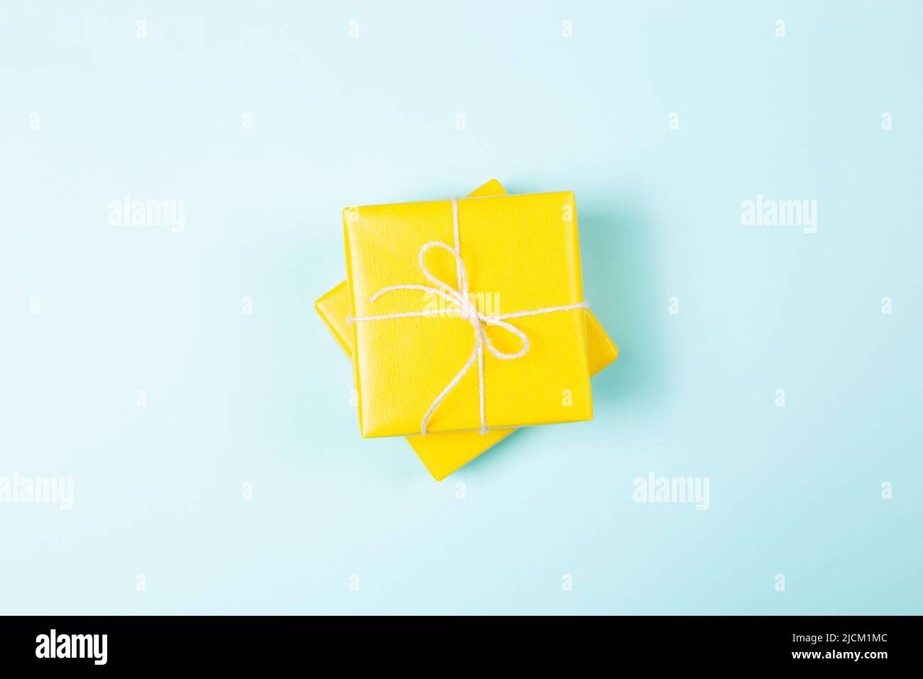 Two yellow packed square gift boxes on pastel blue background. Flat lay ...