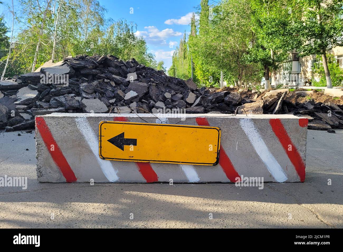 The road is blocked with concrete blocks due to repairs with a detour ...