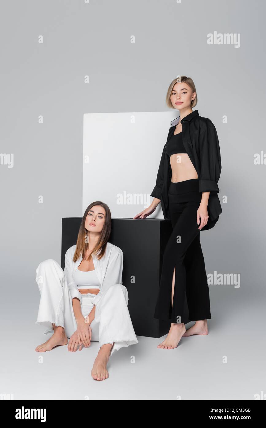 barefoot models in shirts and trousers posing near black and white ...