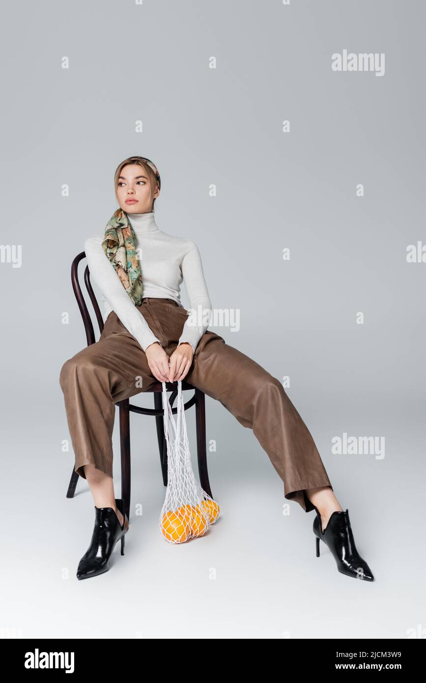 full length of woman in beige trousers sitting on chair with ripe ...