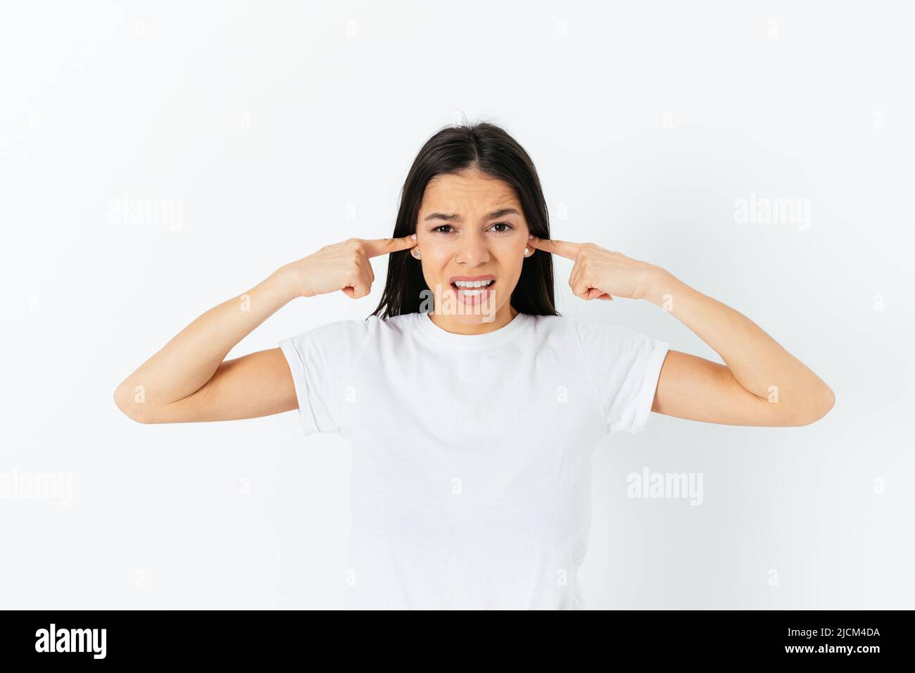 Annoyed young woman covers her ears to avoid hearing unpleasant noise ...