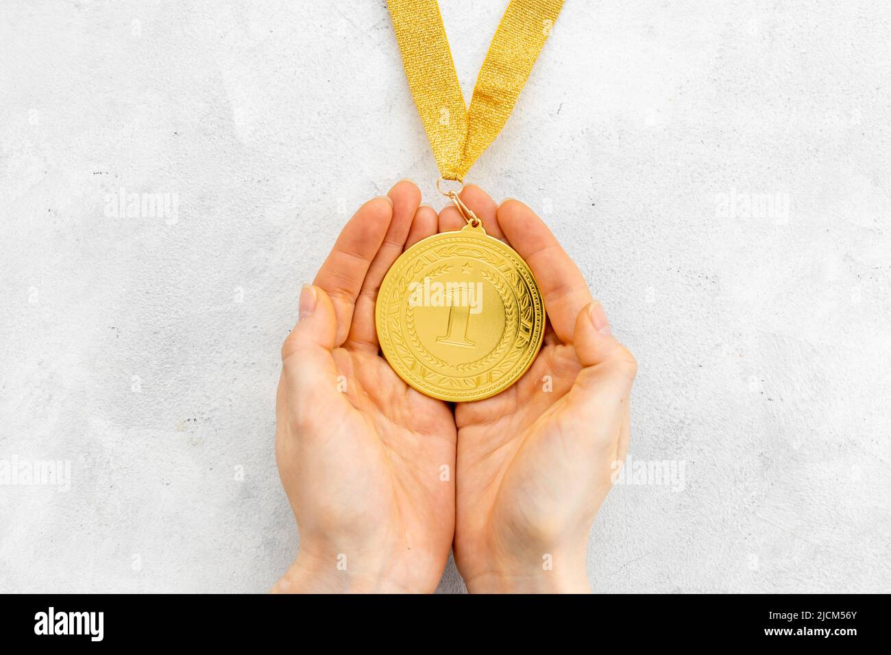 Hand holding up gold medal first place. Winner concept Stock Photo - Alamy