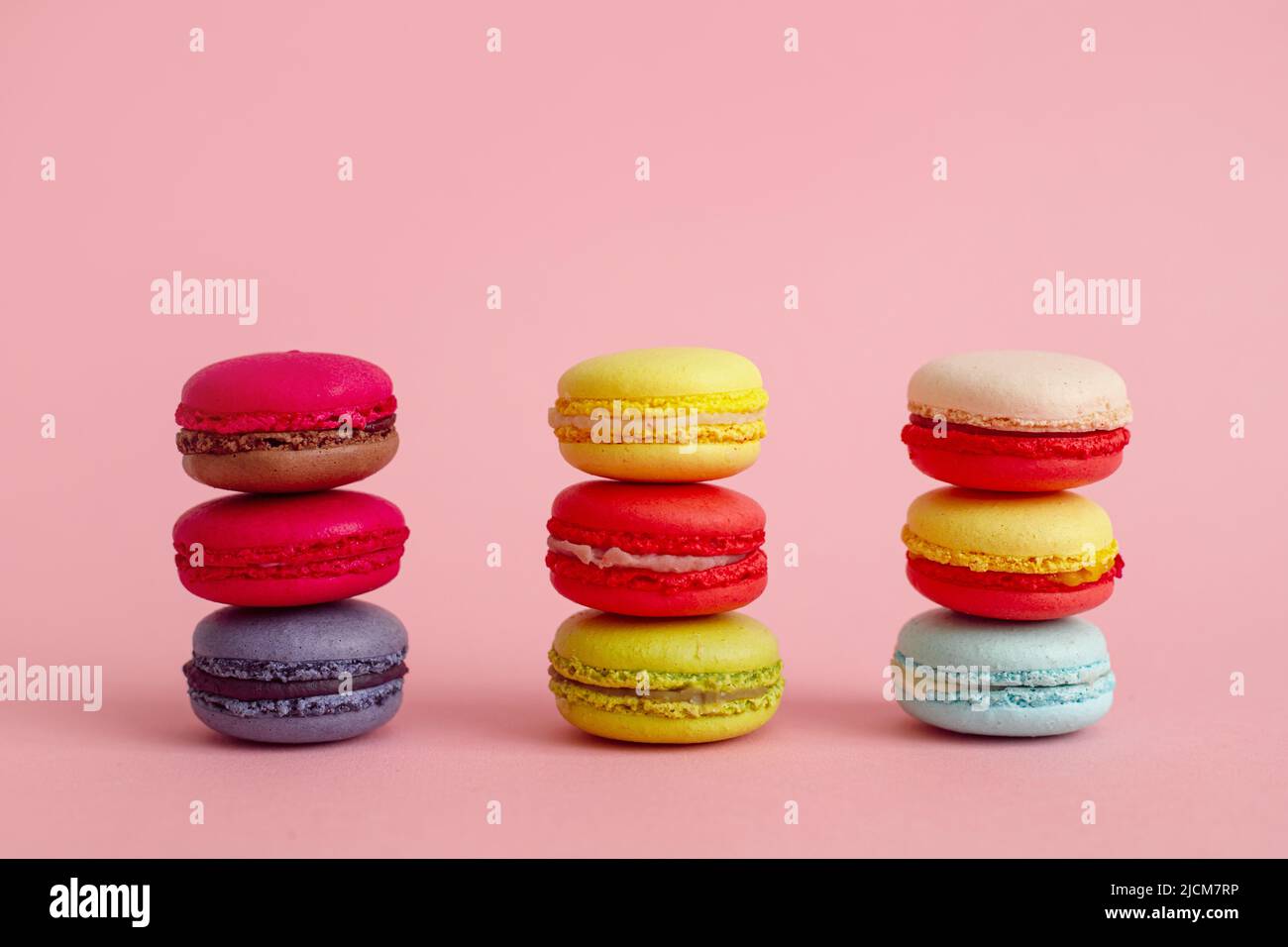 Three stacks of colourful french macaroons or macaron on pink ...