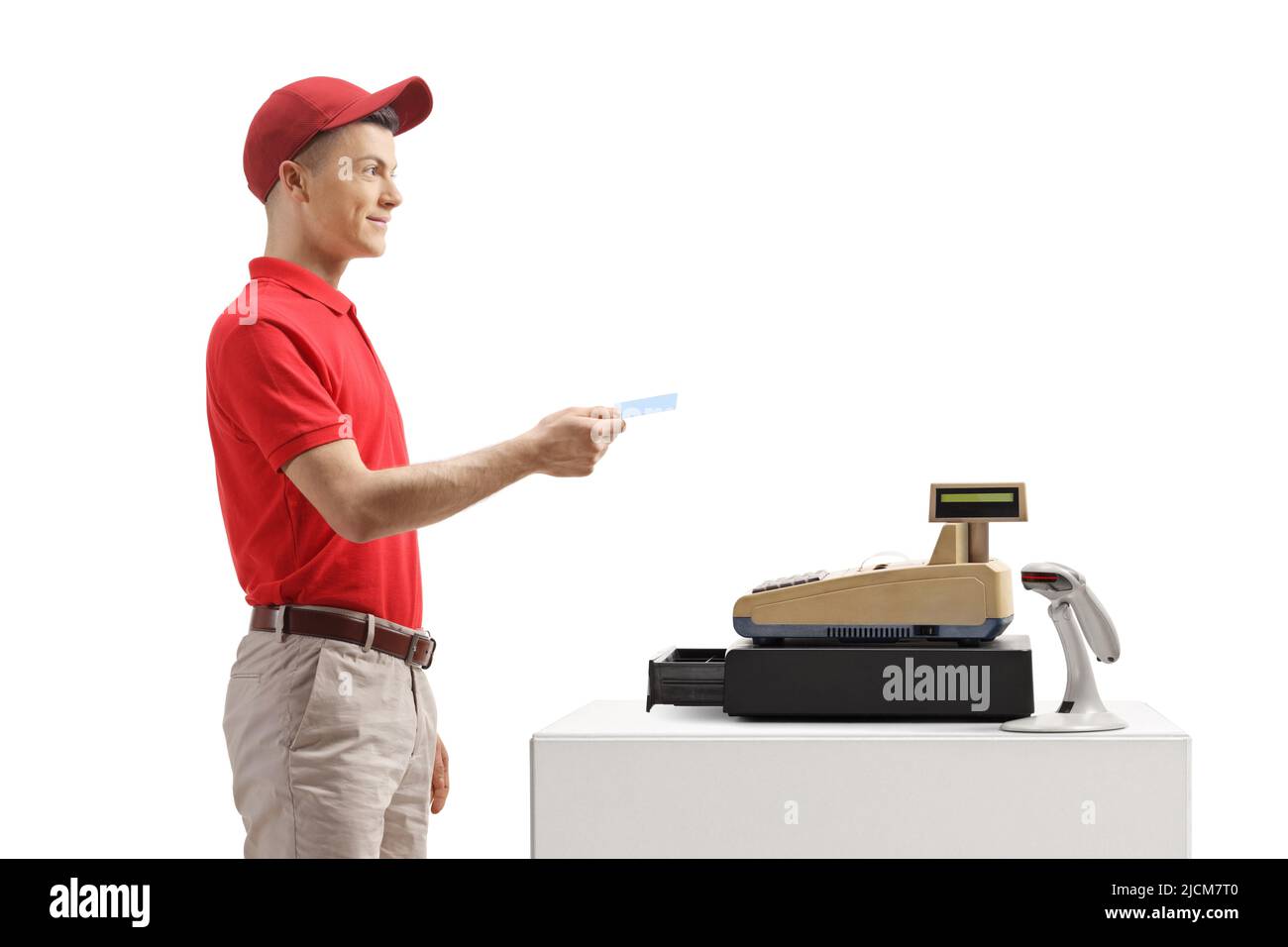 Young male worker at a cash register holding a credit card isolated on ...