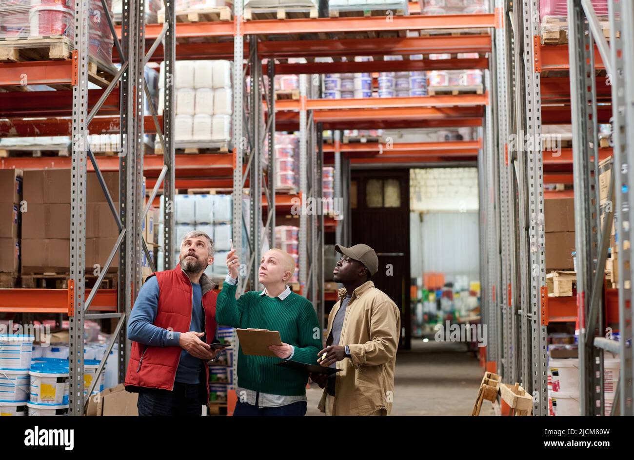 Woman pointing up on the shelves and counting goods together with her ...