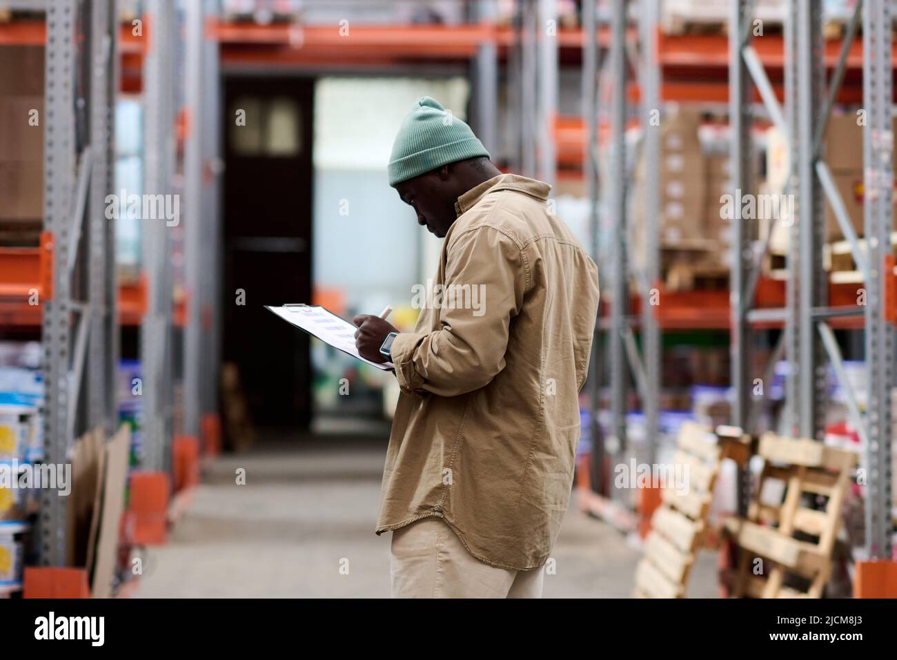 African American young supervisor making notes in document during his ...