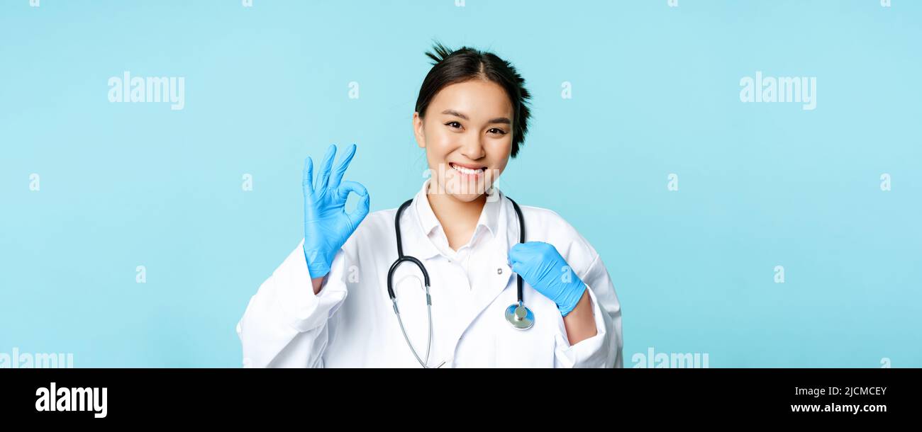 Smiling asian doctor, female physician touching stethoscope, showing ...