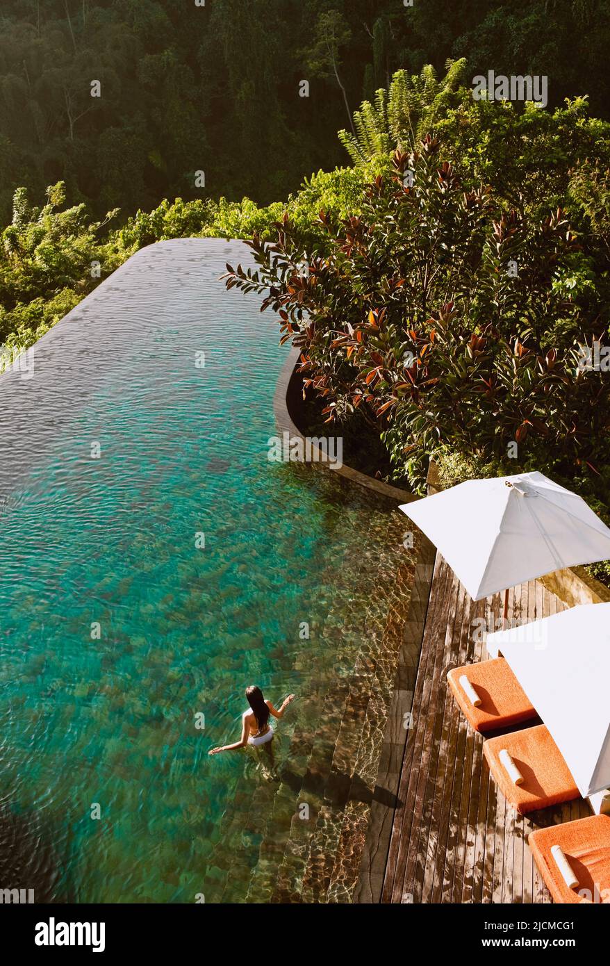 Woman wading in main infinity pool, Ubud Hanging Gardens, Bali ...