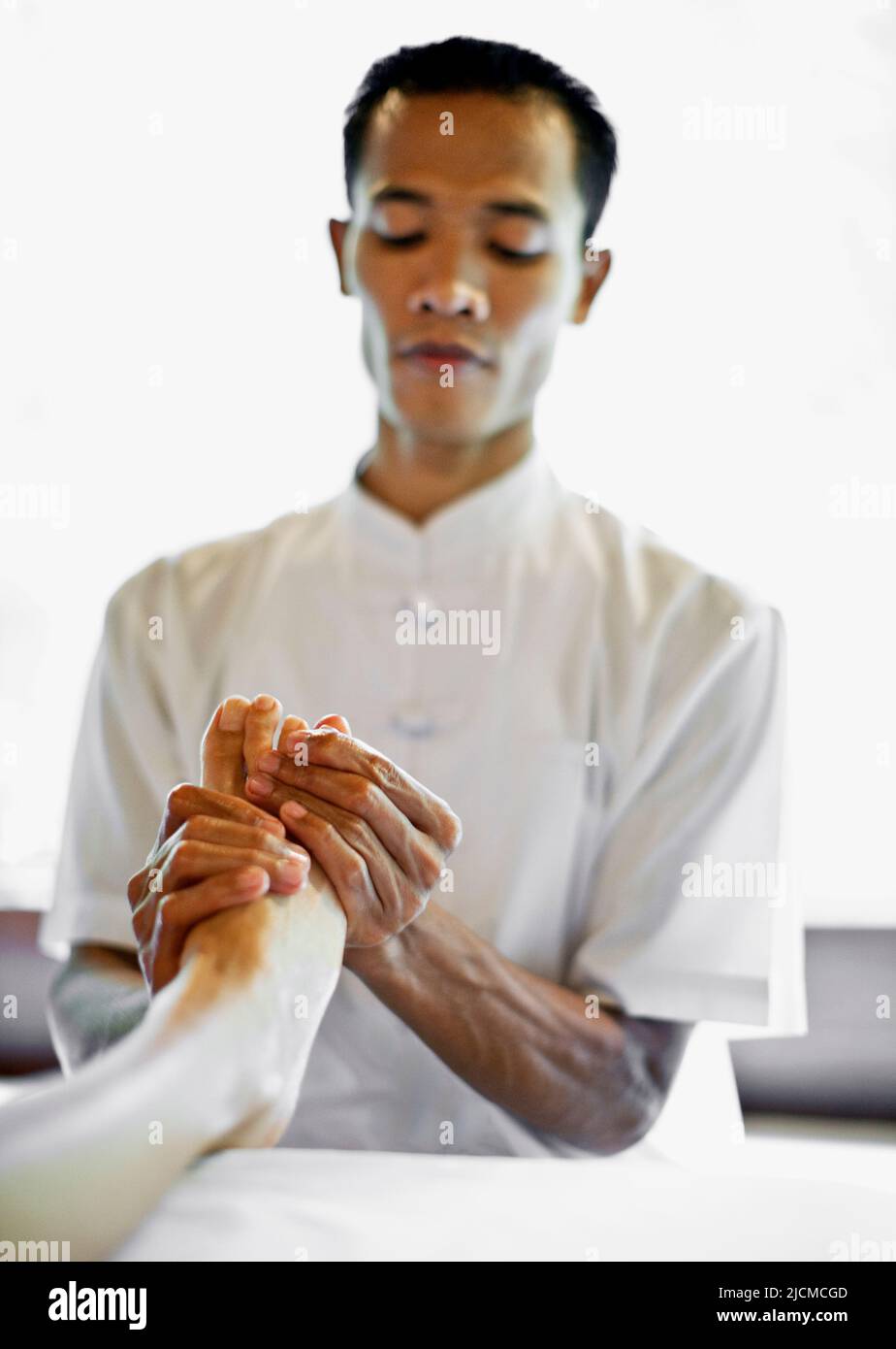 Balinese Male Spa Therapist Giving Foot Refloxology Massage At Ayung