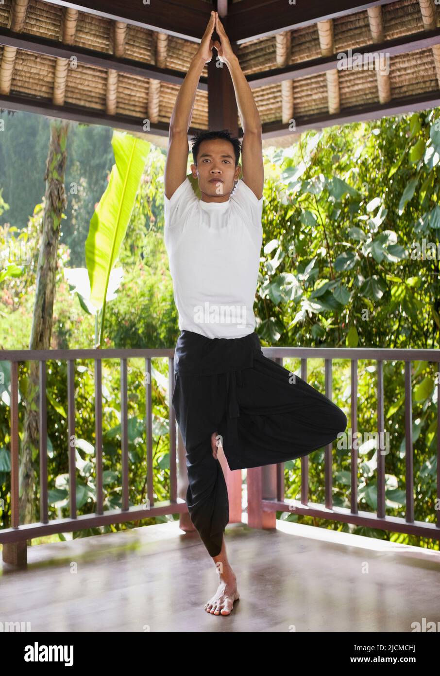 Young Balinese man practicing yoga in the open-air yoga pavilion at ...