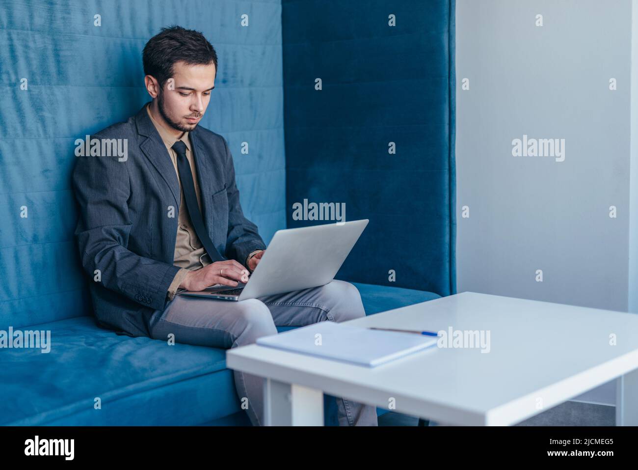 Portrait of young businessman working on laptop while sitting alone in an office cubicle Stock ...