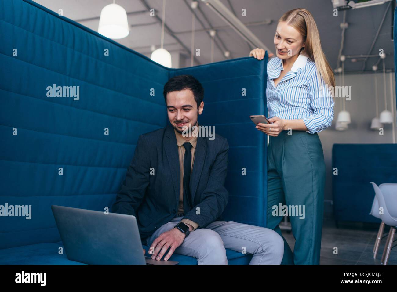 Man on break sits with laptop woman stands next to him looks at screen ...