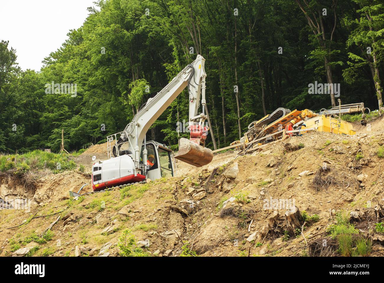 Excavator working on construction of higway on the steep slope of the ...