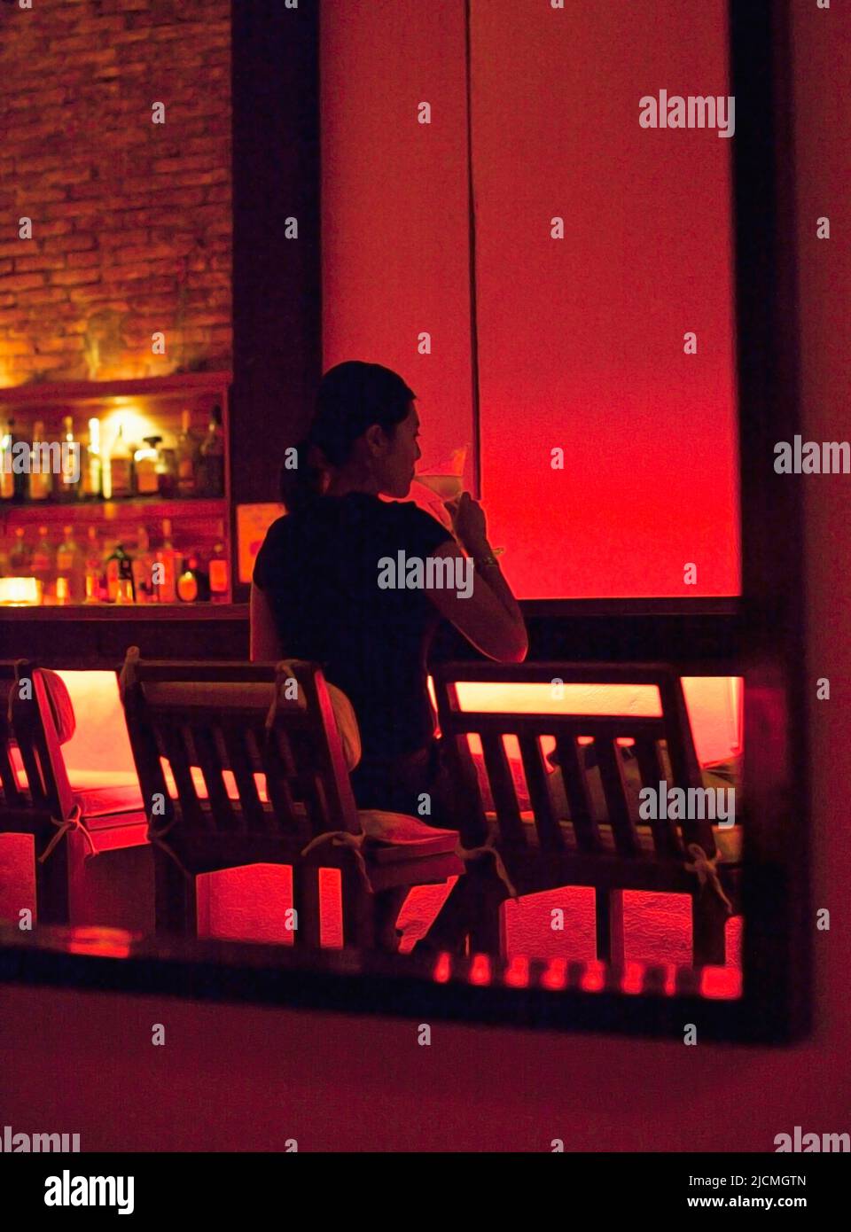 A young Asian woman sips a martini at a bar. Vientiane, Laos P.D.R ...