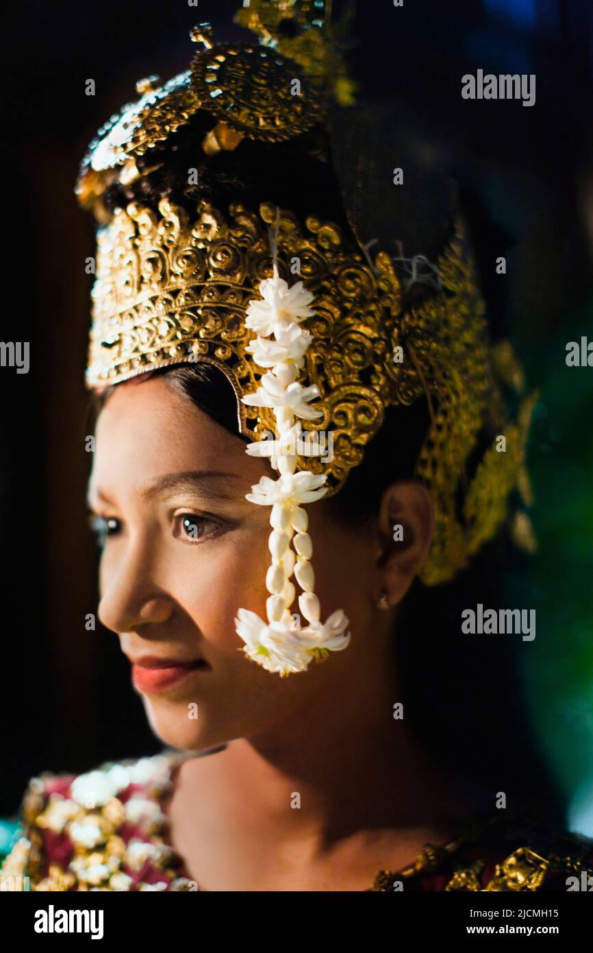 A young Cambodian Apsara dancer walks on a pathway at dusk. Siem Reap ...