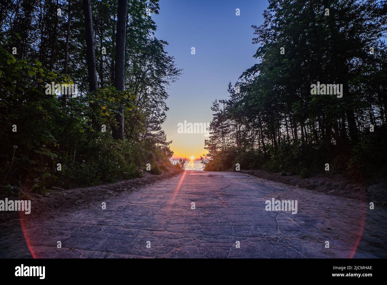 concrete path leading to the beach in the sun beams. Landscape at ...