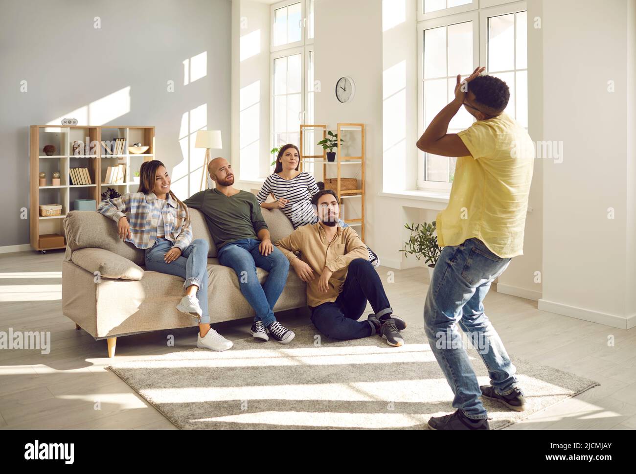 Group of young cheerful friends have fun playing charades during casual ...