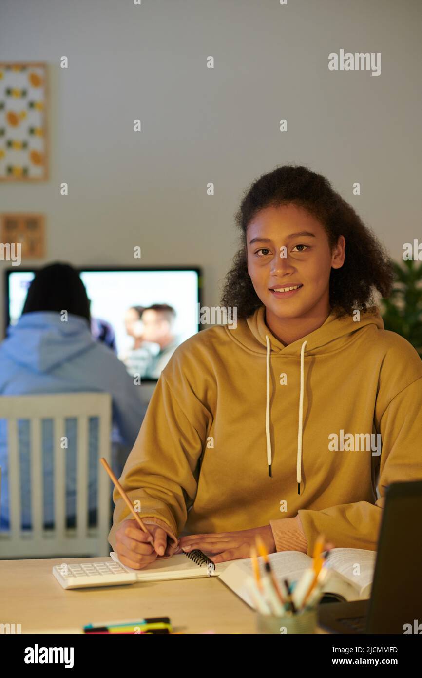 Smiling high school student doing homework when her sister ha Indian ...