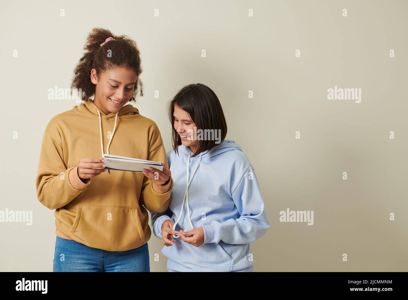 Cheerful girl supporting her friend who received acceptance letter from ...