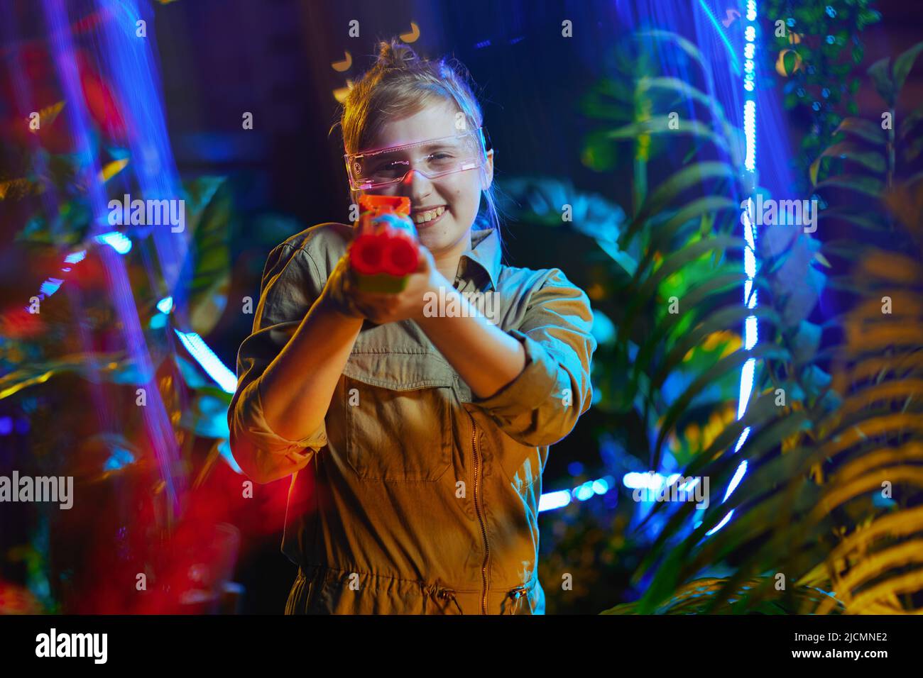 happy stylish child with toy gun and futuristic glasses in virtual ...