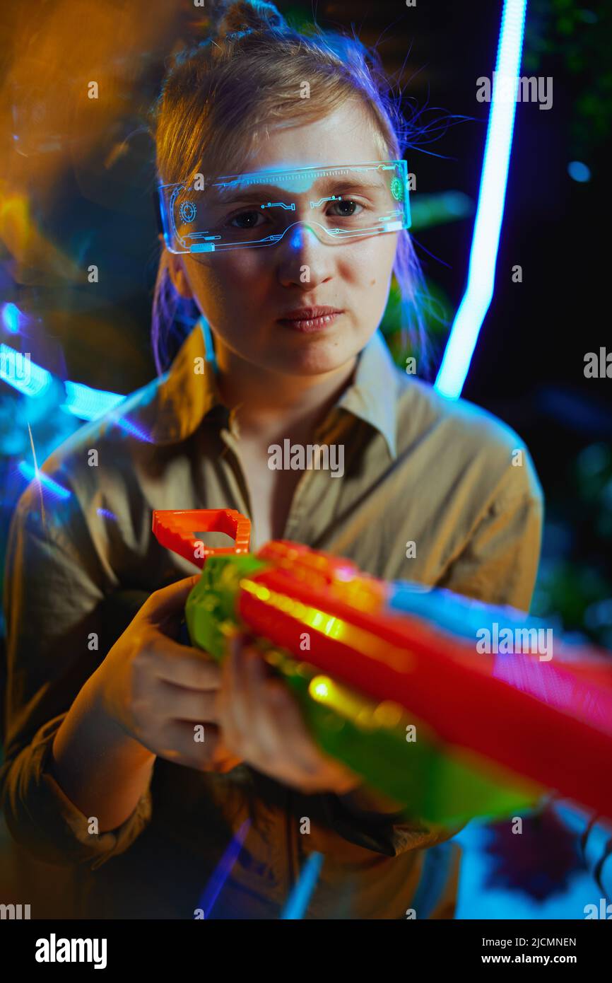 trendy girl with toy gun and futuristic glasses in virtual reality ...