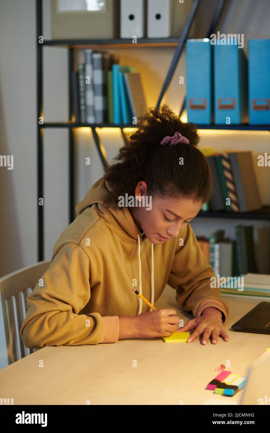 Schoolgirl writing difficult words on sticky notes when studying for ...