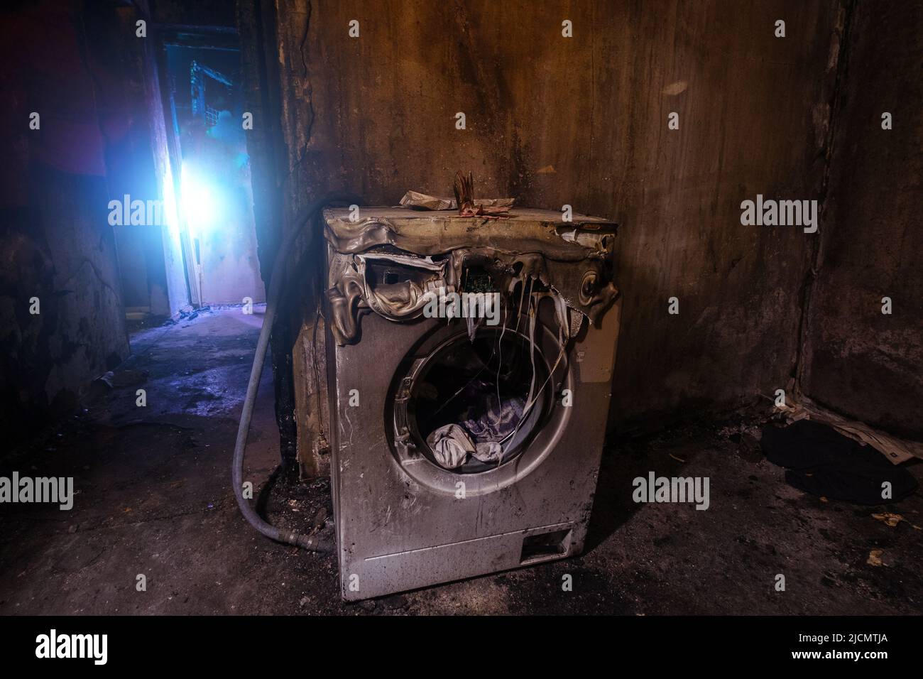 Burnt house interior. Fused remains of furniture and washing machine ...