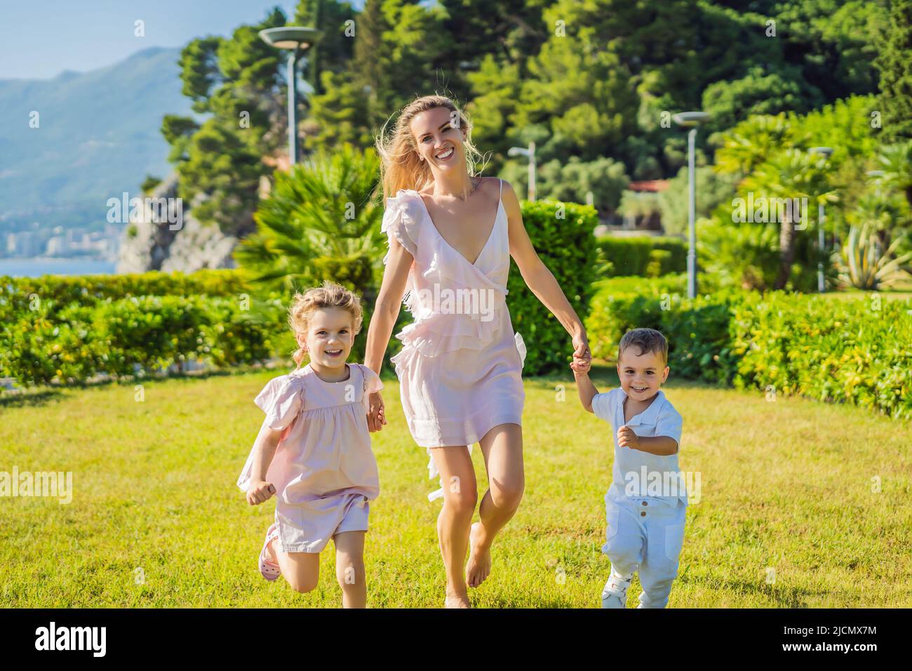 Joyful young mother playing catch together with two little children ...