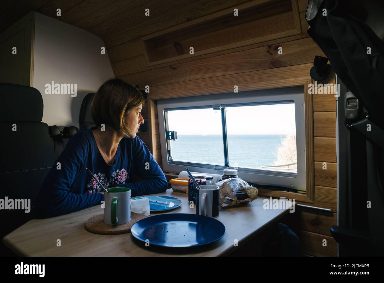 Concept: Camper van. Girl with pajamas looking at the landscape through ...
