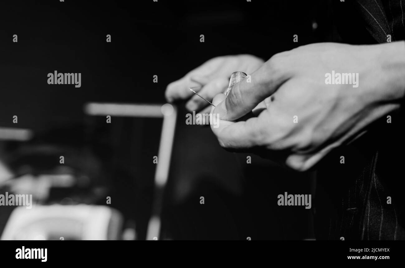 Tailor's hand. Male hands with a needle, thread and thimble. Conceptual ...