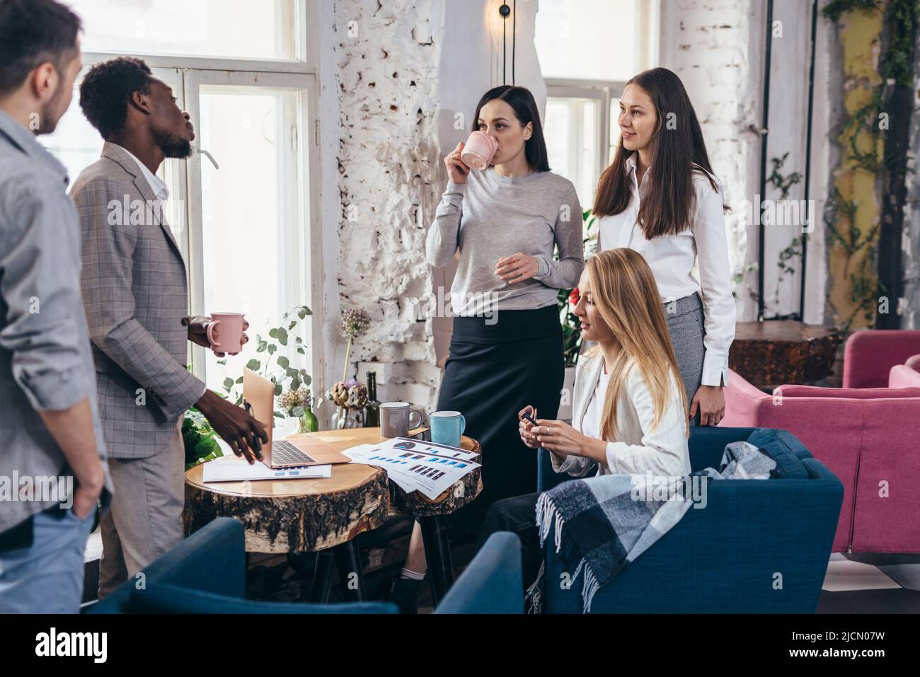 Group of employees meeting around table in cafe Stock Photo - Alamy
