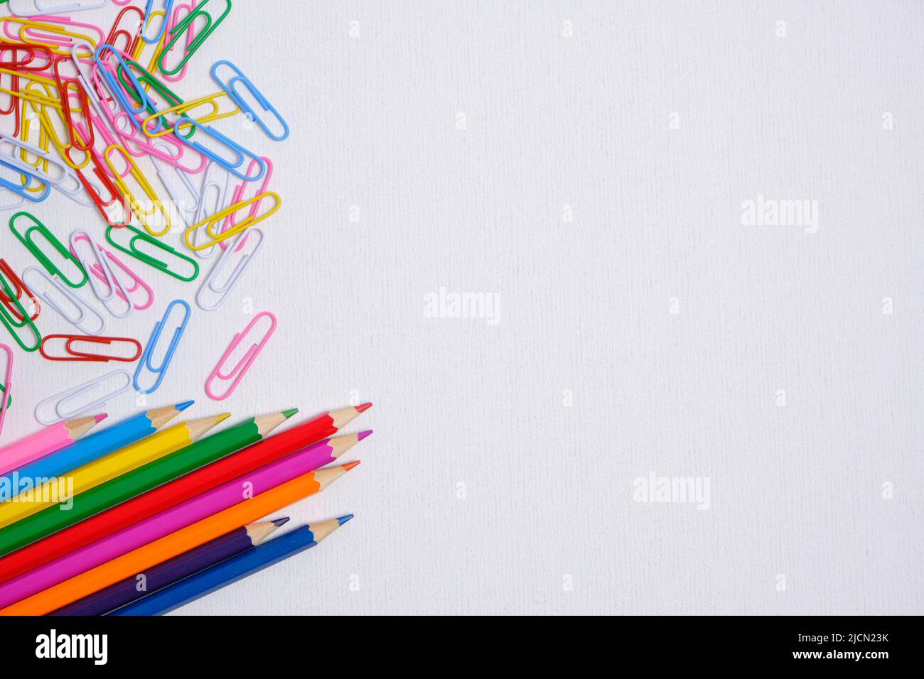 Colored pencils and paper clips white background, school supplies and ...