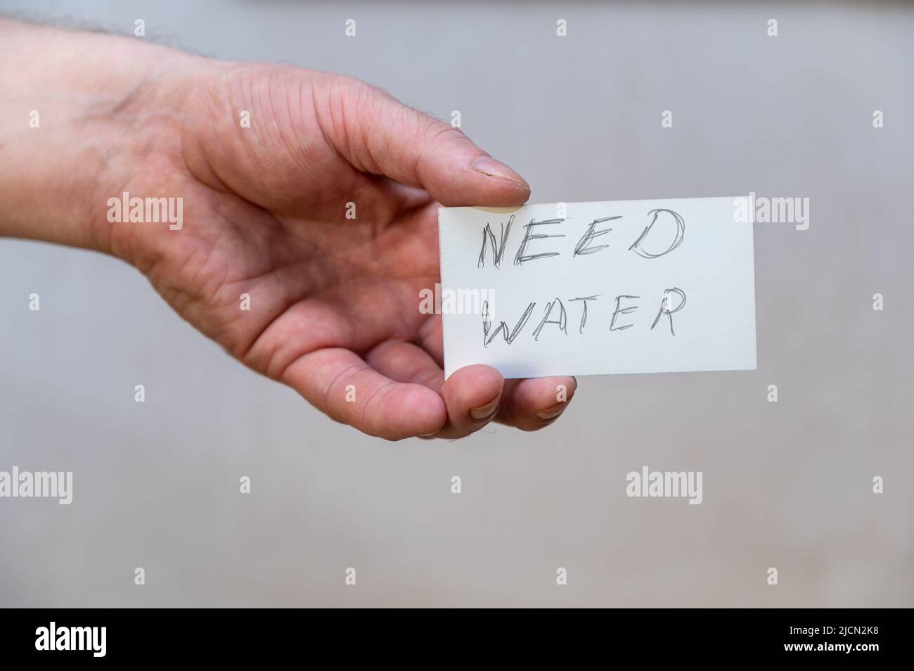 Need water. Words written in jagged letters. A man's hand holds a white ...