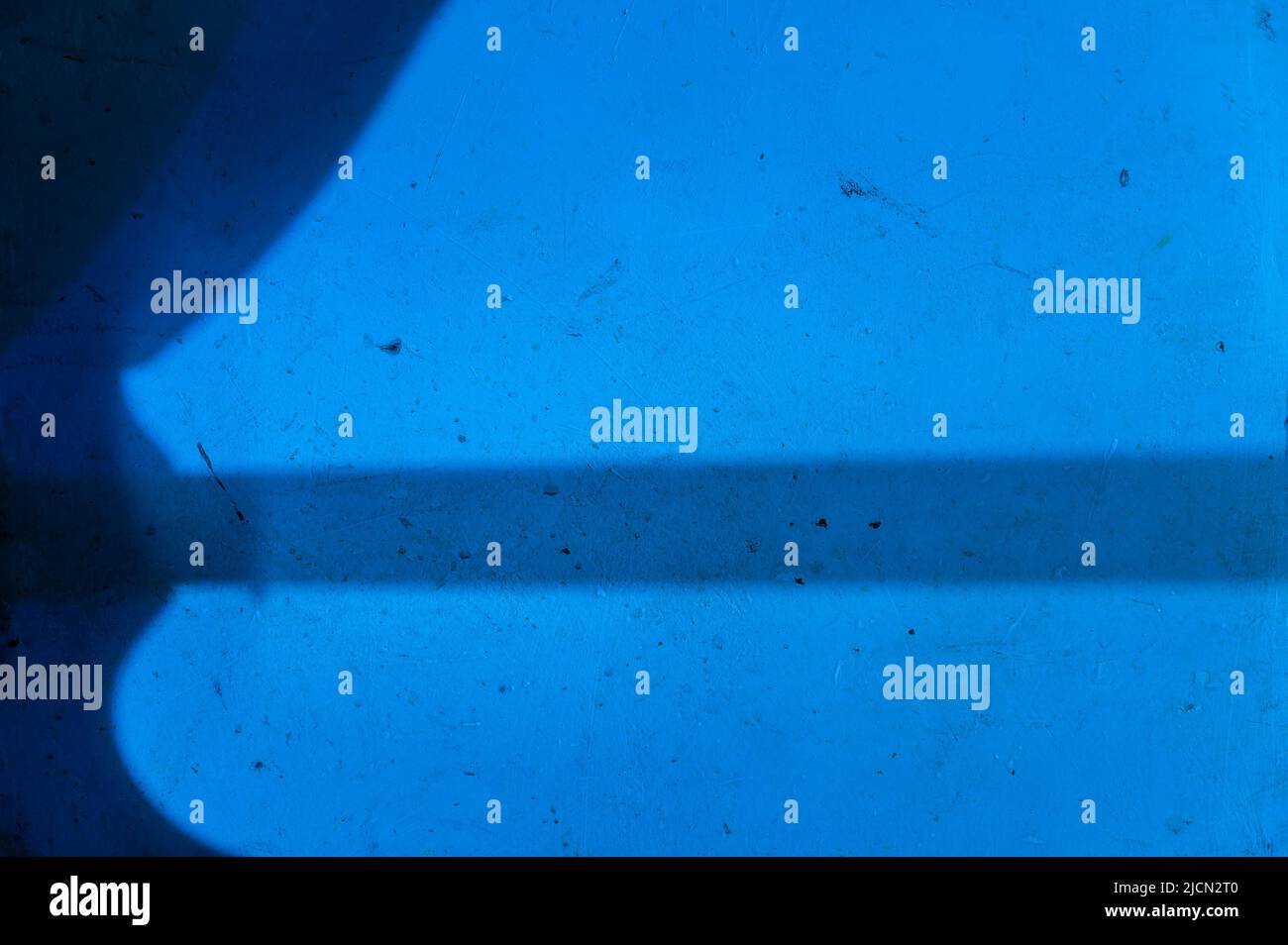 Night shadows on the blue wall. Abstract gray silhouette on a rough ...